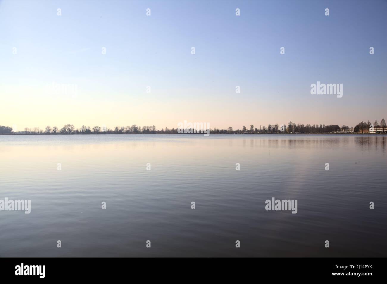 Lake with a shore counterlit by the sun on a clear day Stock Photo - Alamy
