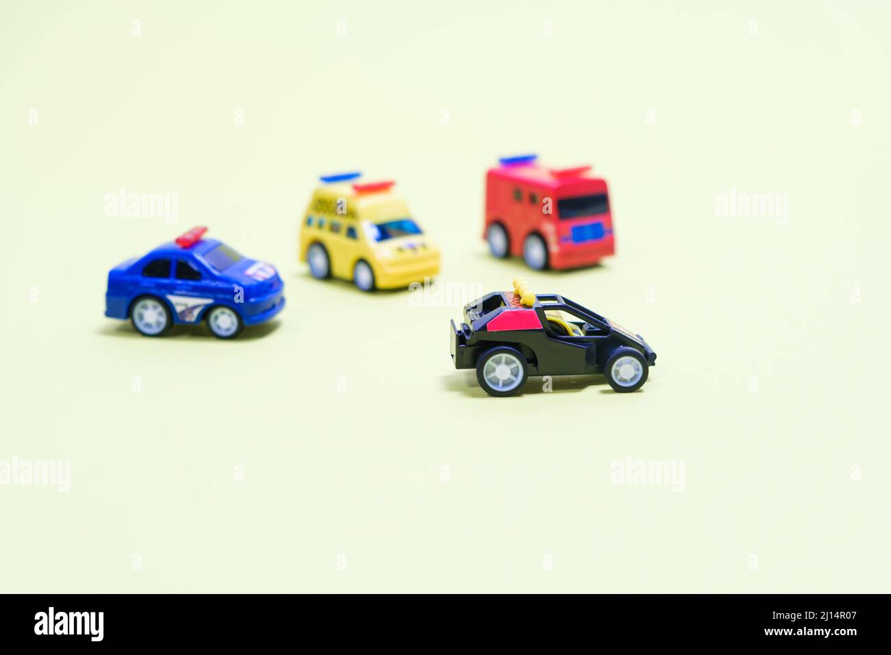 Toy plastic little cars on a light yellowish background with a place ...