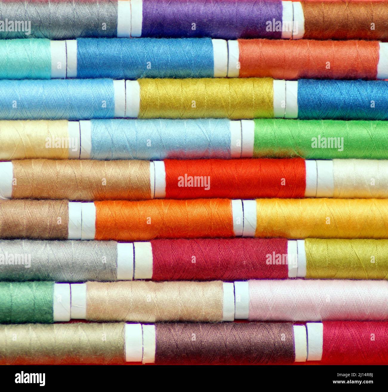 macro shot of rows of spools of multicolored sewing thread, laid ...