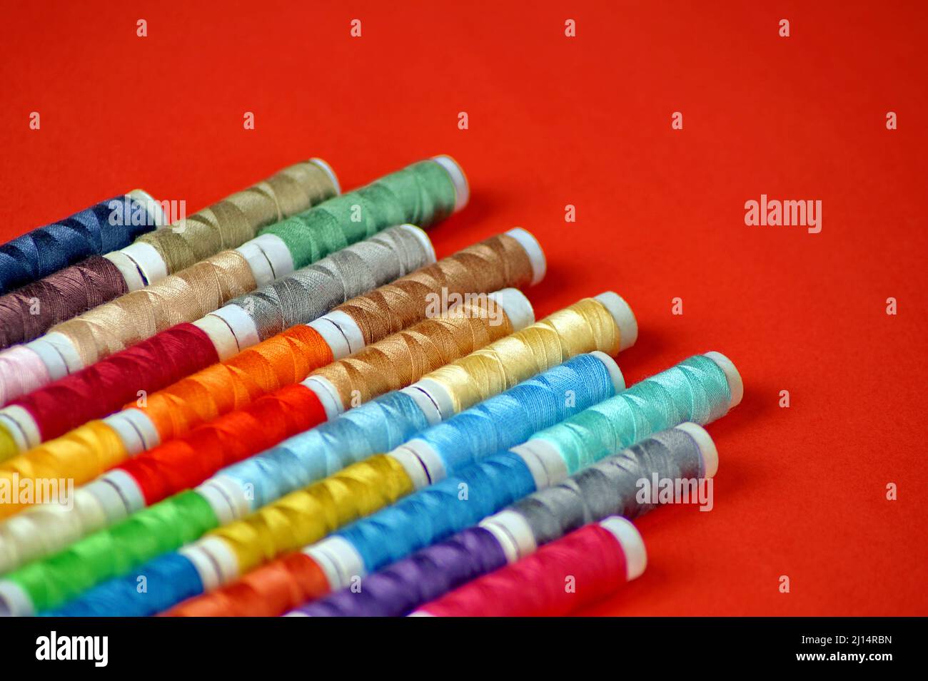 on a red background, there are spools of colored thread in the lower ...