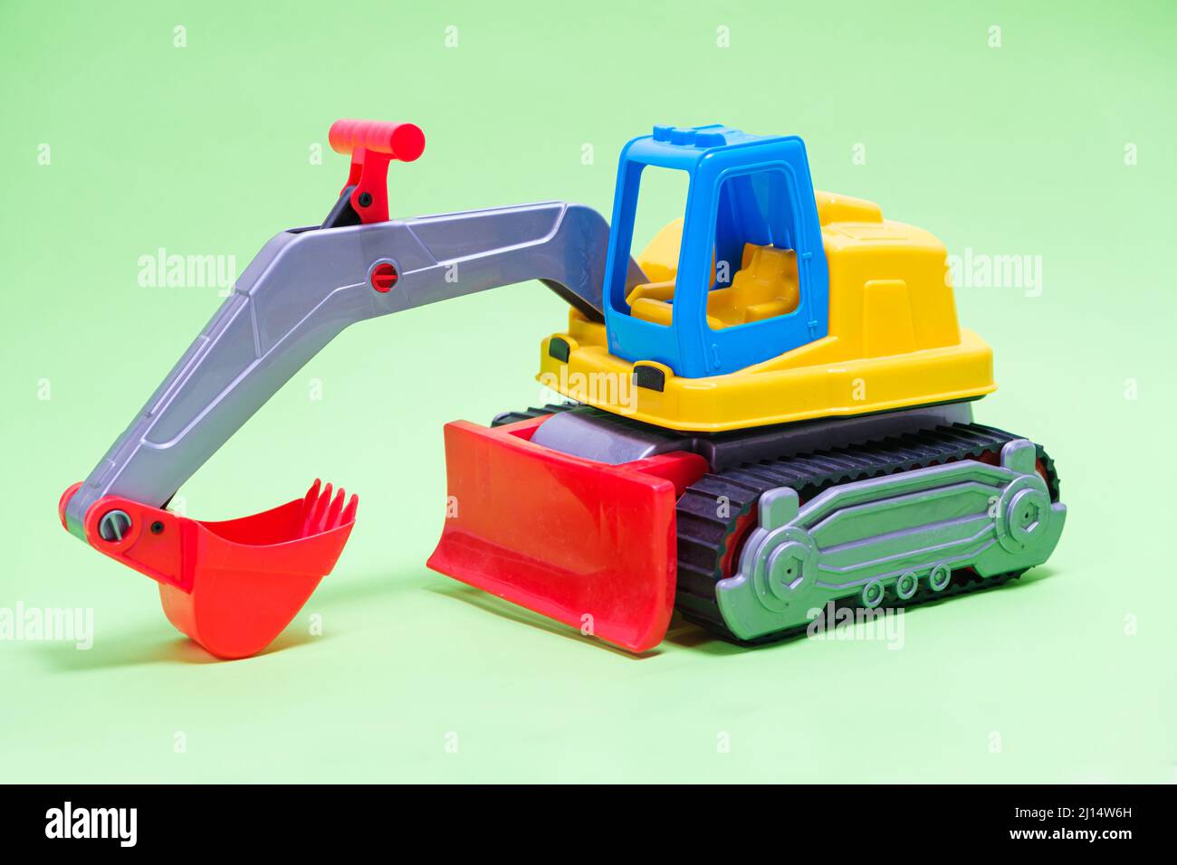 Yellow excavator plastic car on green background. Construction ...
