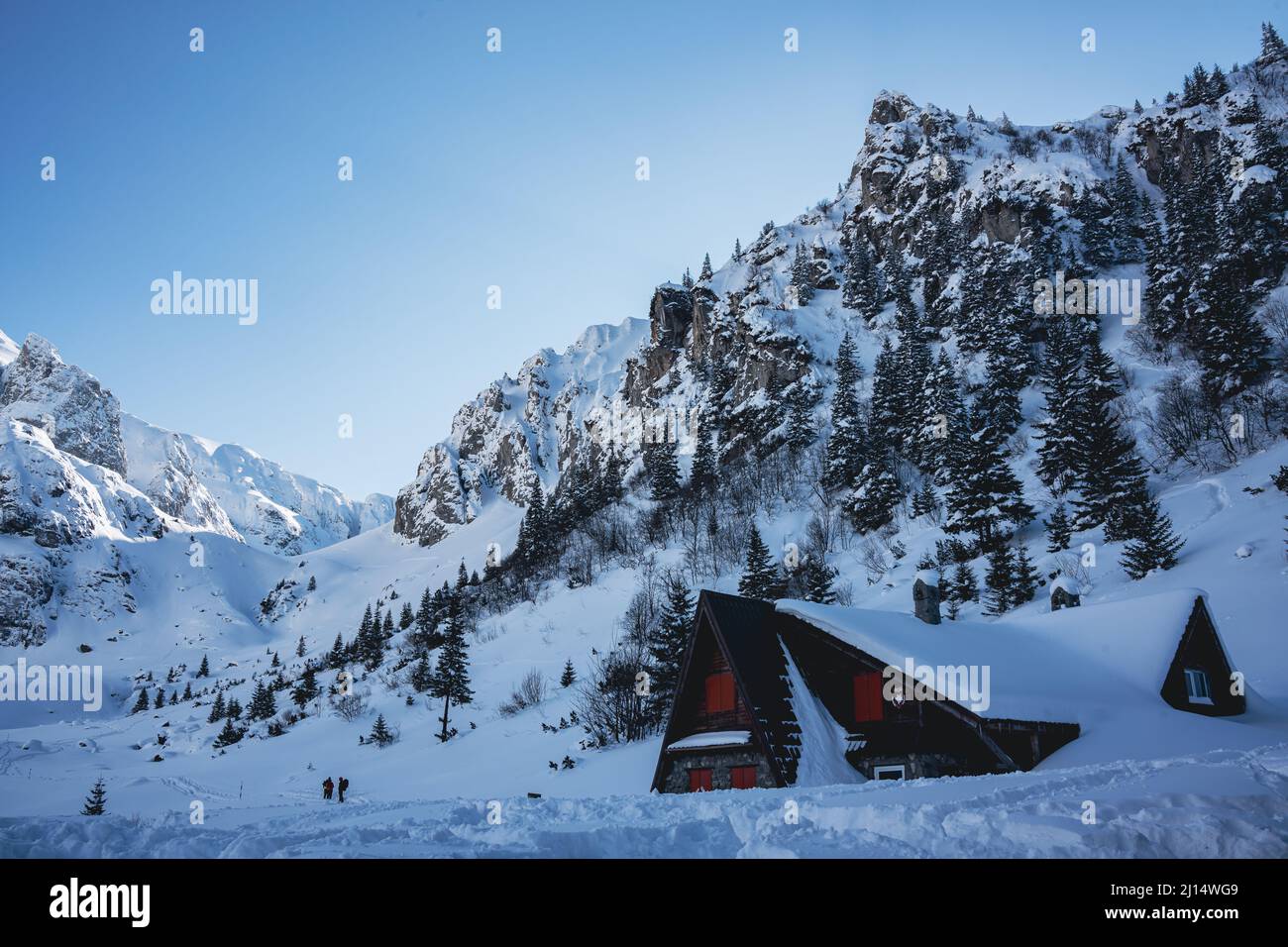 Small house surrounded by beautiful snowy forested mountains Stock ...