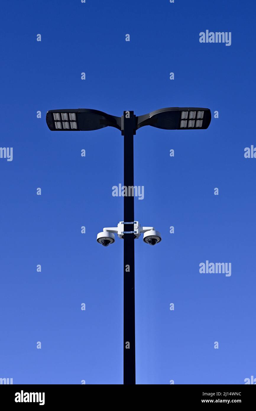 Low angle shot of security cameras hanging on a black street lamp pole ...
