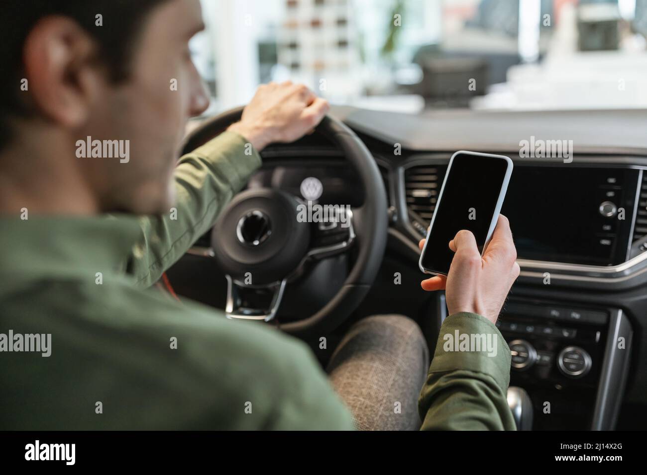 Unrecognizable young man using smartphone, sitting in drivers seat of ...