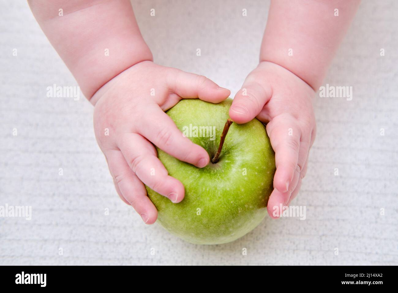 Baby hand and green apple fruit, close-up. Children fingers and an ...