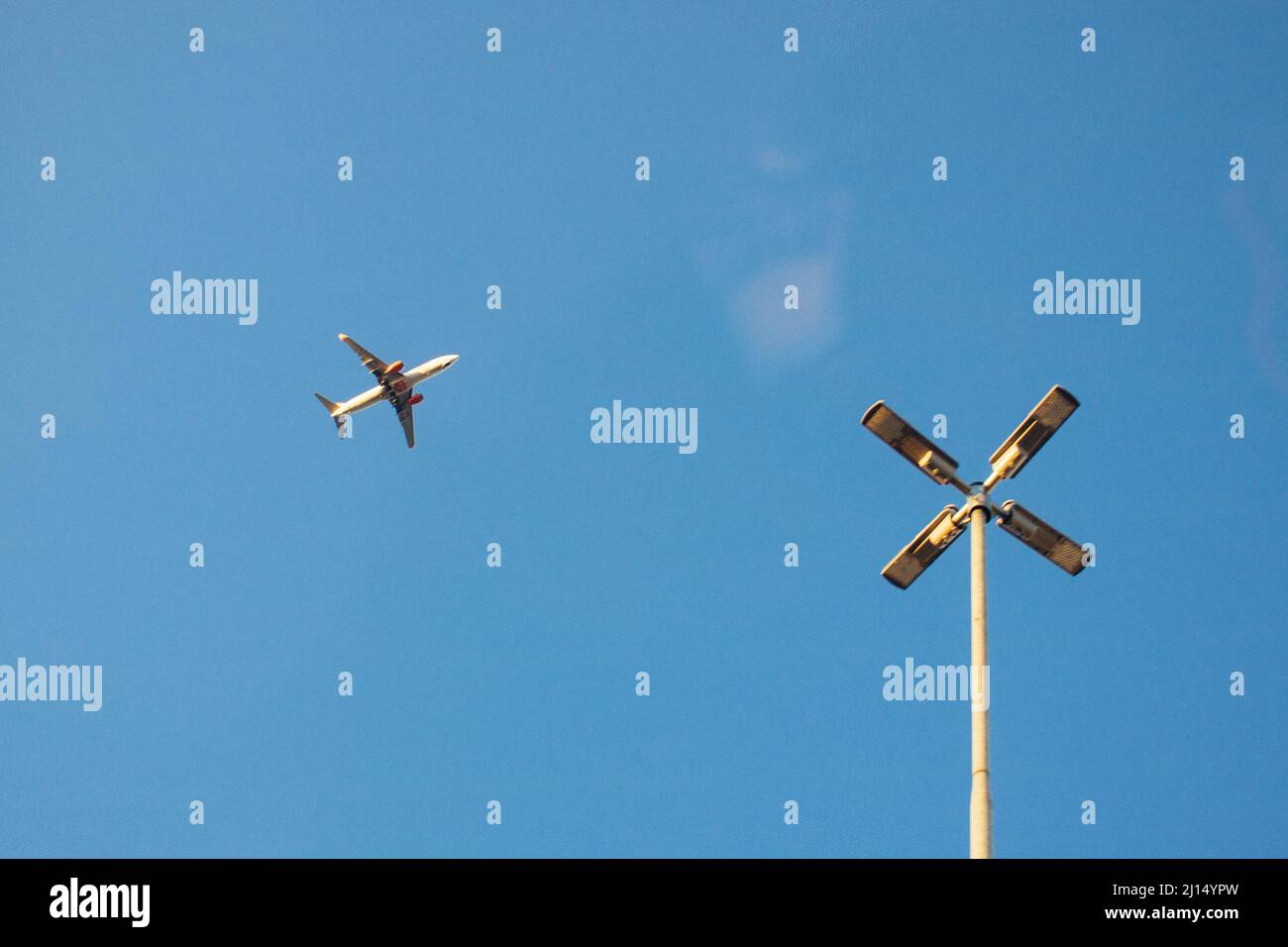 High lantern on the street and an airplane flying in the blue sky Stock ...