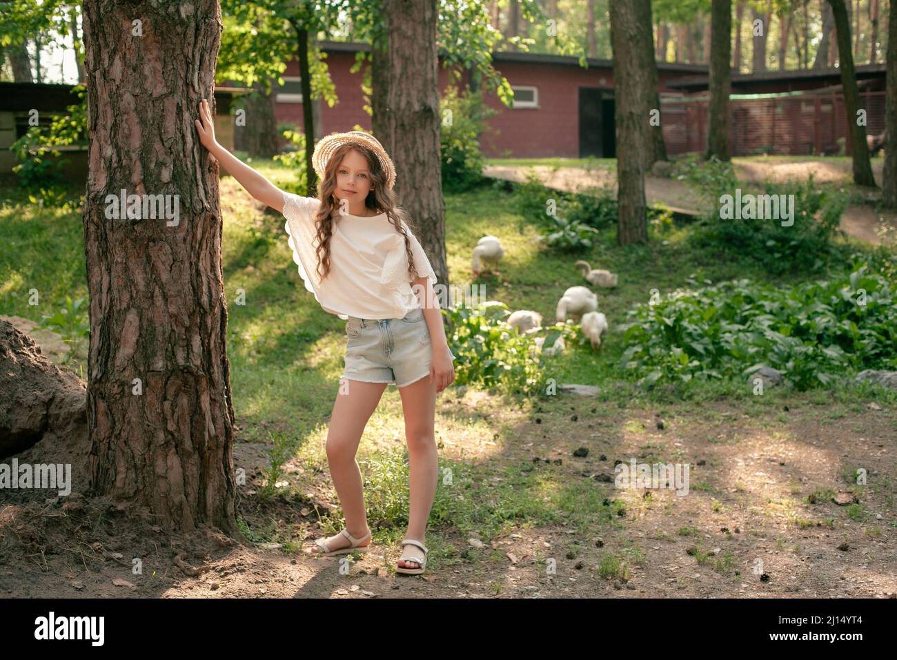 Full-length portrait of tween girl leaning of tree in courtyard of ...
