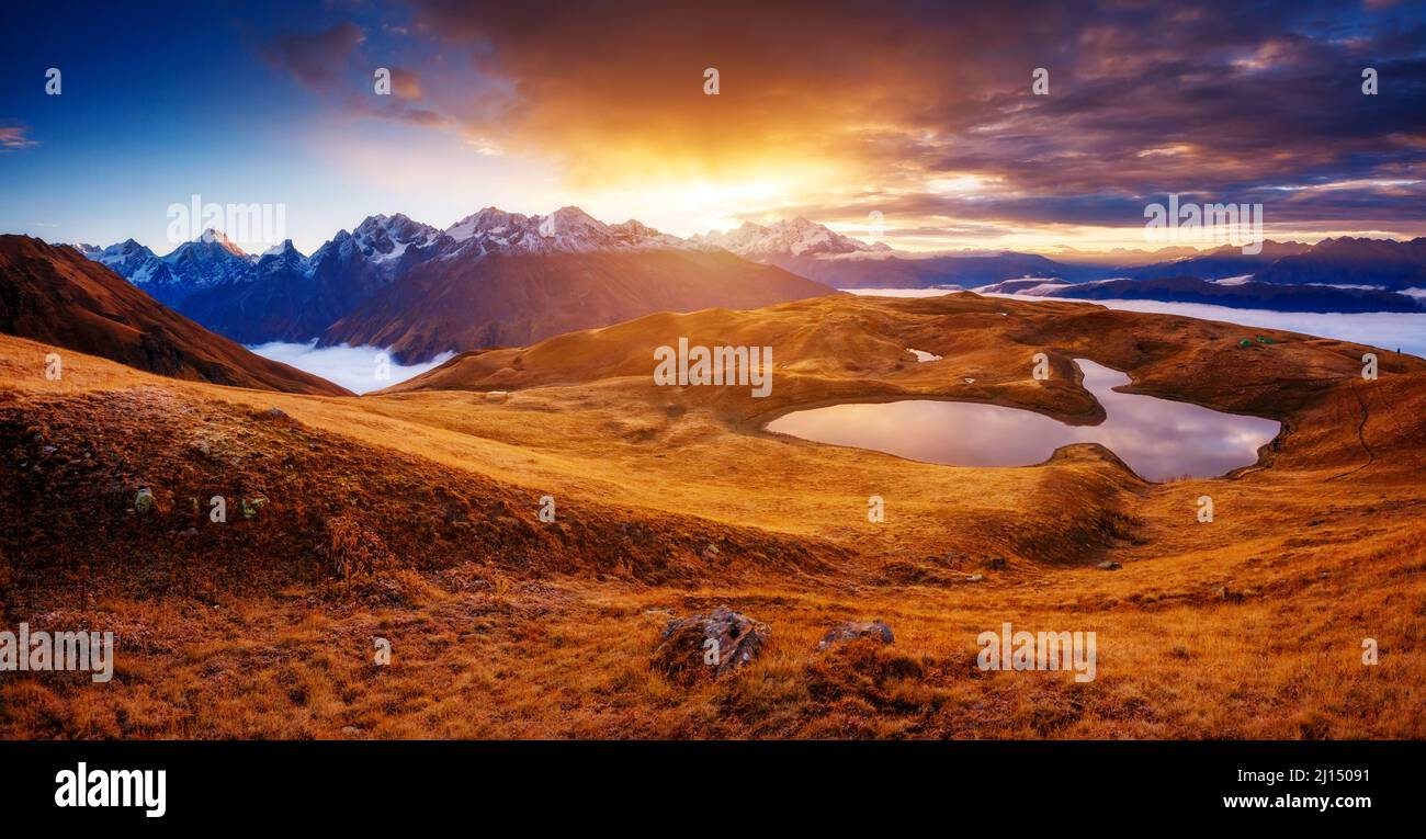 Fantastic lake Koruldi with overcast red sky at the foot of Mt. Ushba ...