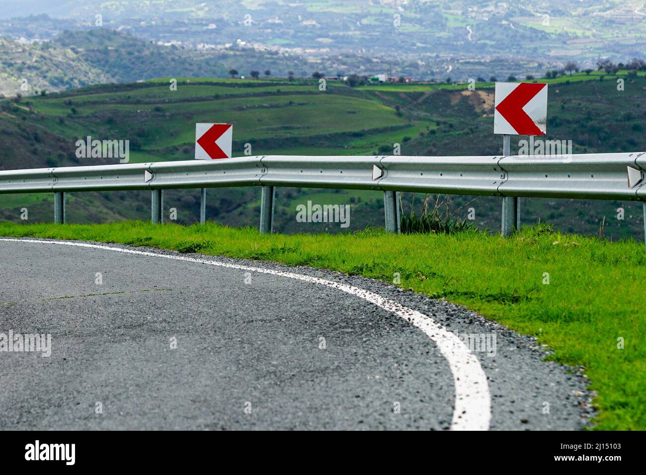 red and white warning sign arrows before a dangerous road bend in a ...