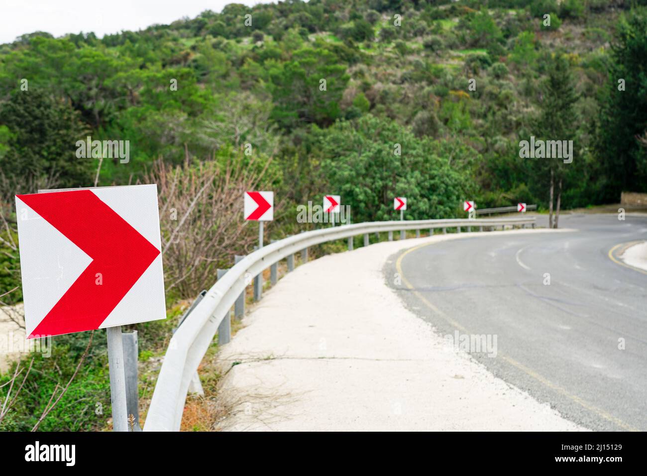 red and white warning sign arrows before a dangerous road bend in a ...