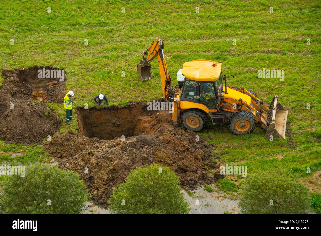 Excavator digs a hole to repair sewer pipes for sewage, workers control ...