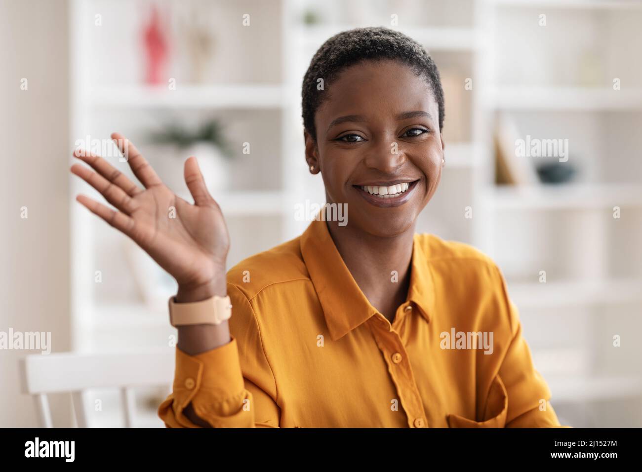 Happy young black woman posing at home, waving at camera Stock Photo ...