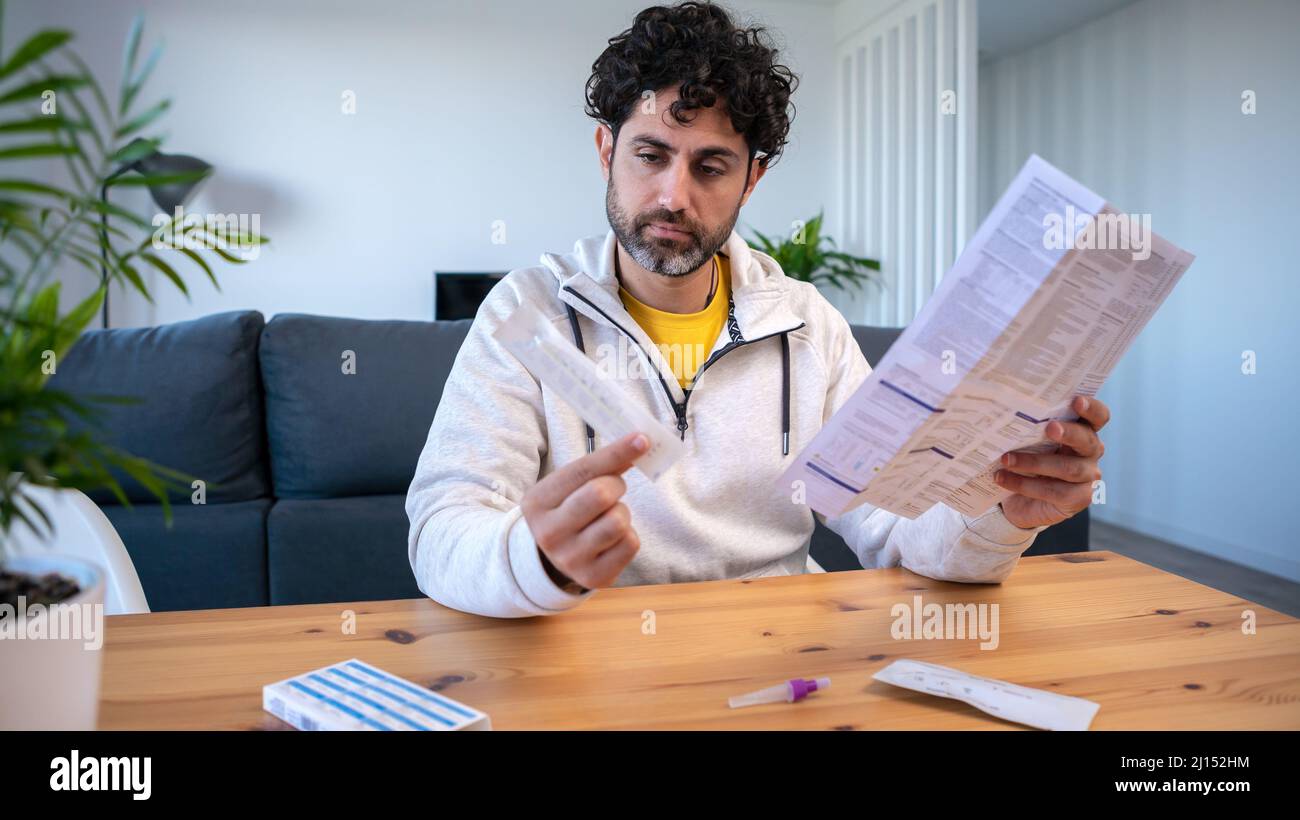 Caucasian man wearing mask reading instructions for used a sample covid ...