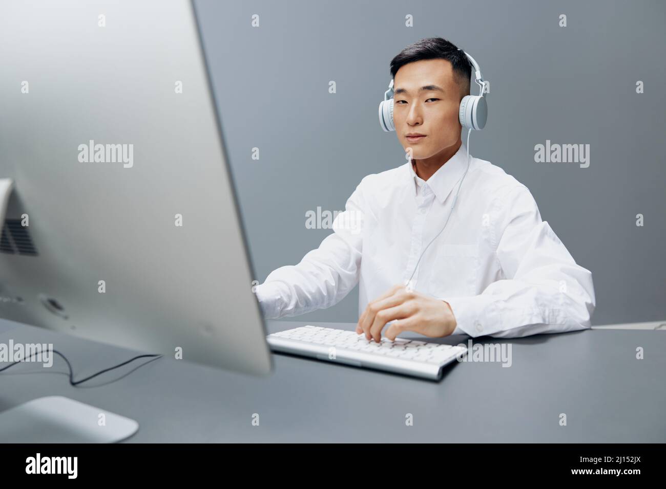 Asian man in headphones at the table in front of the computer Lifestyle ...
