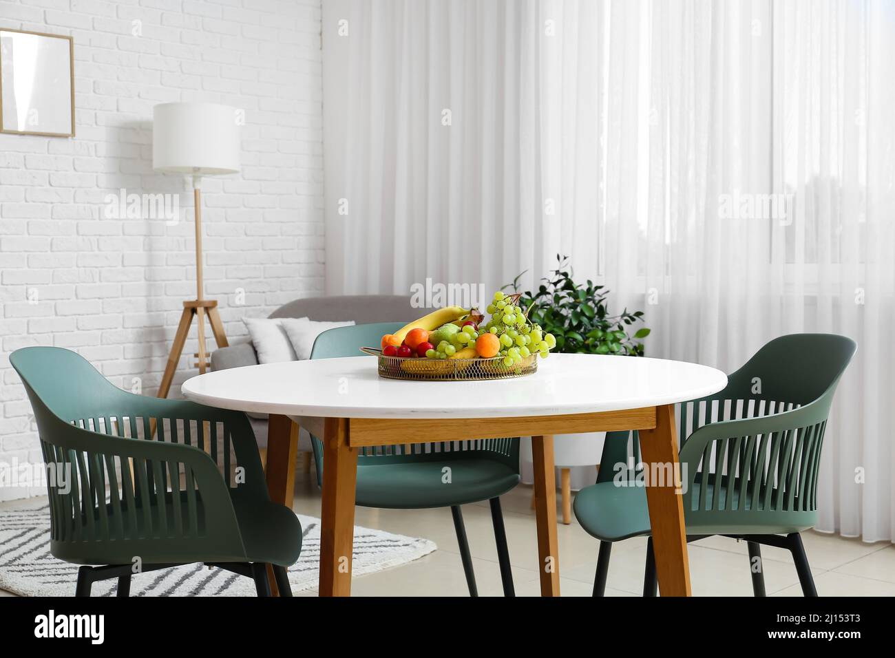 Dining table with fruit basket in light room Stock Photo - Alamy