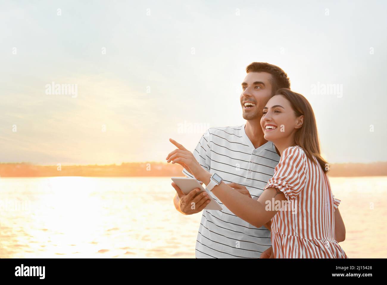 Couple of young tourists with tablet near river Stock Photo - Alamy