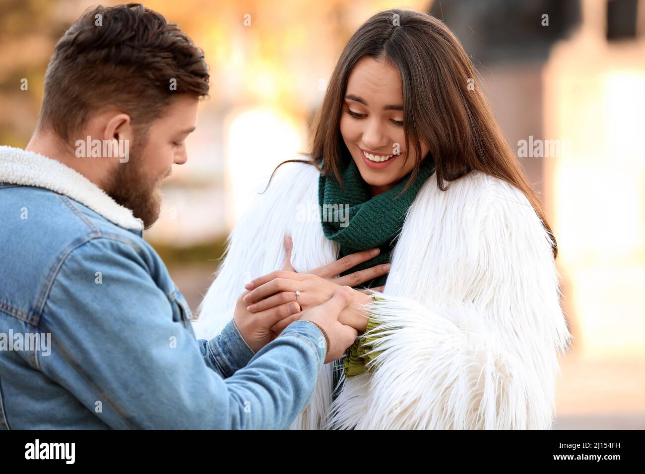 Young man putting ring on finger of his fiancee after marriage proposal ...
