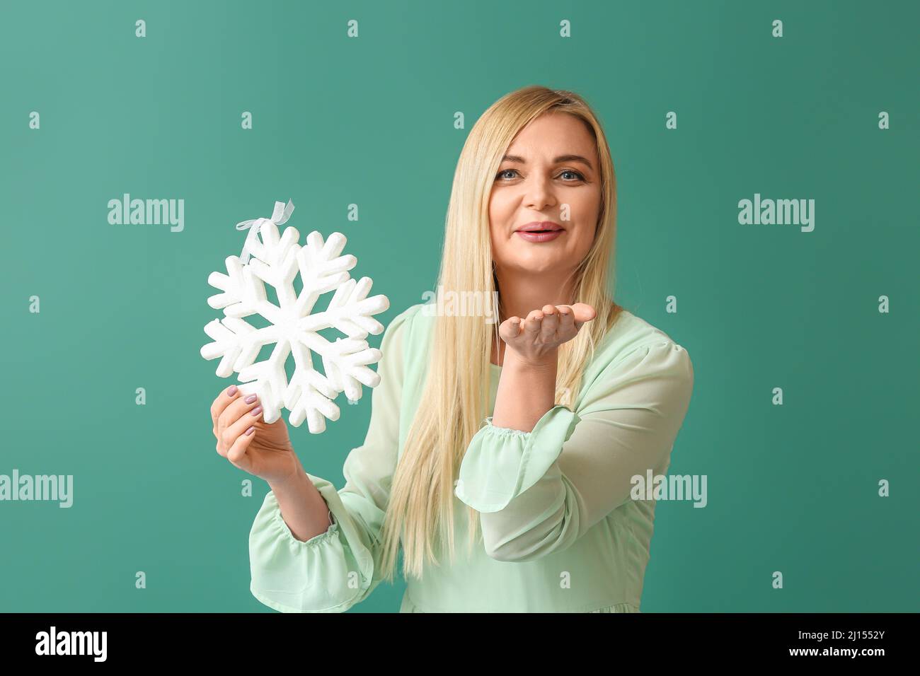 Beautiful woman with snowflake blowing kiss on green background Stock ...