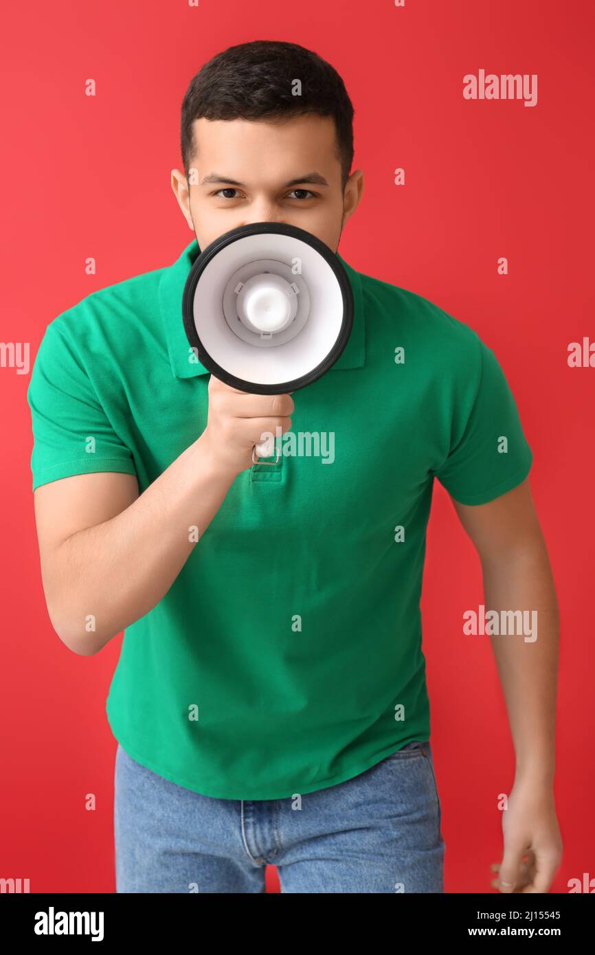 Young man shouting into megaphone on red background Stock Photo - Alamy