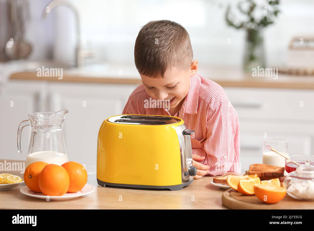 Cute little boy with yellow toaster in kitchen Stock Photo - Alamy