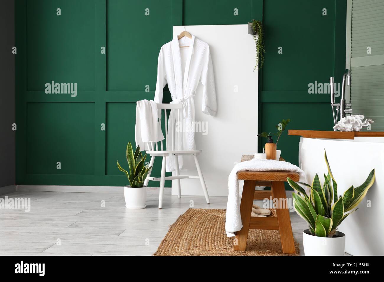Interior of stylish room with white bathrobe, houseplants and bench ...