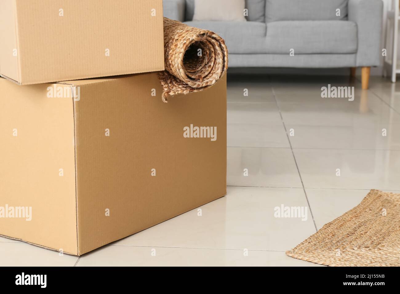 Cardboard boxes with wicker carpets in room, closeup Stock Photo - Alamy