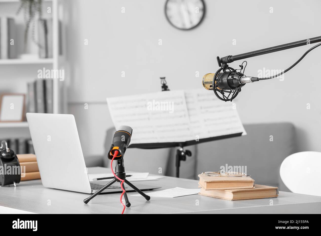Modern workplace with laptop, books and microphones in room Stock Photo ...