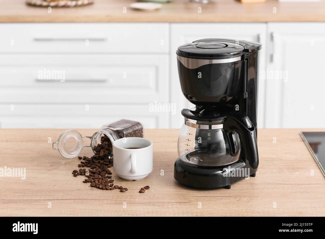 Black coffee machine with cup and jar of beans on counter in kitchen ...