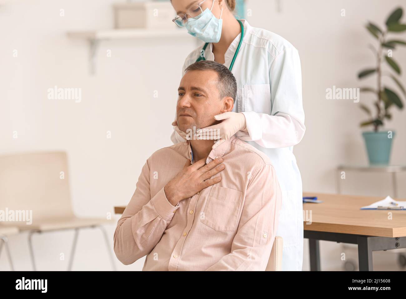 Doctor examining man's neck in clinic Stock Photo - Alamy