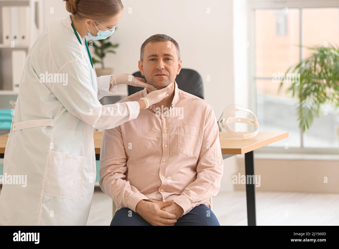Doctor examining man's neck in clinic Stock Photo - Alamy