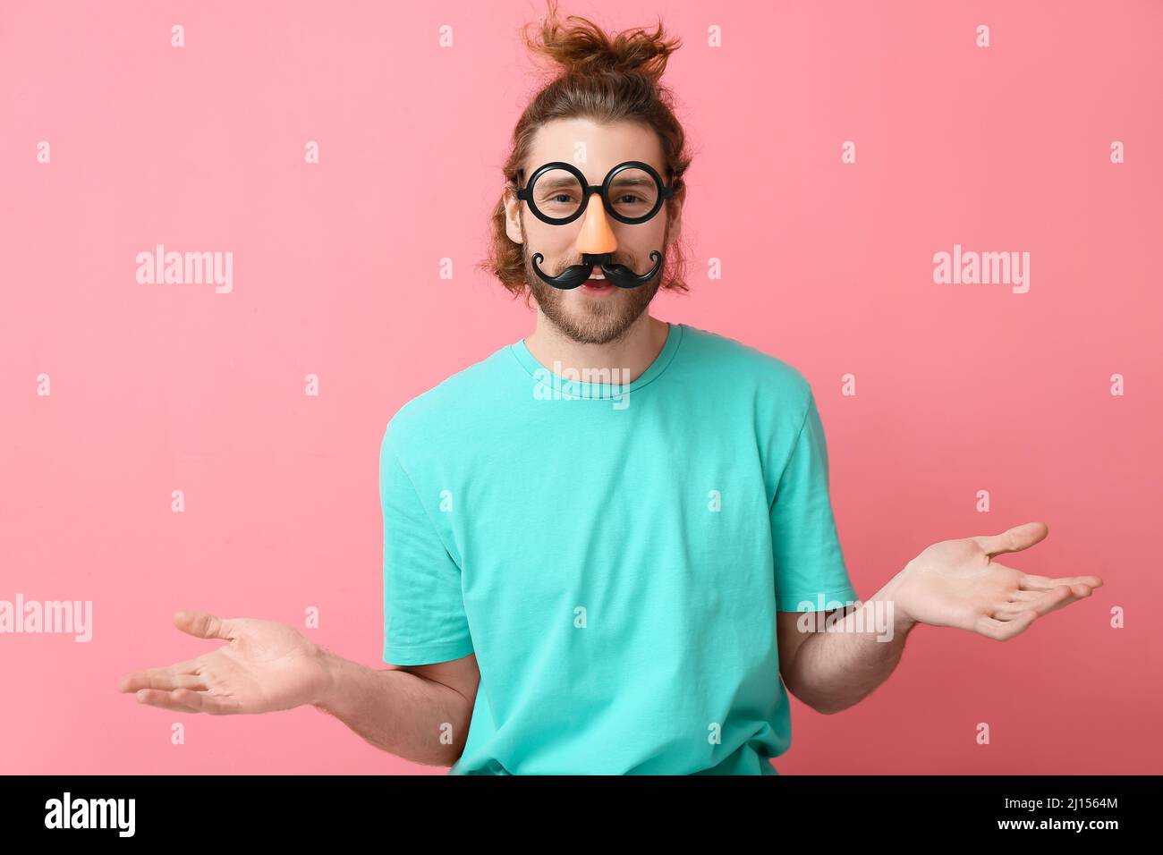 Funny young man in disguise on pink background. April fools' day ...