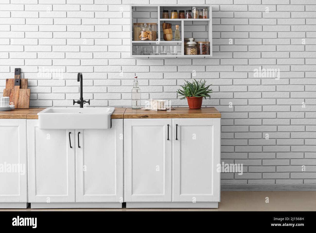 Counters with sink, kitchen utensils and shelving unit hanging on white ...