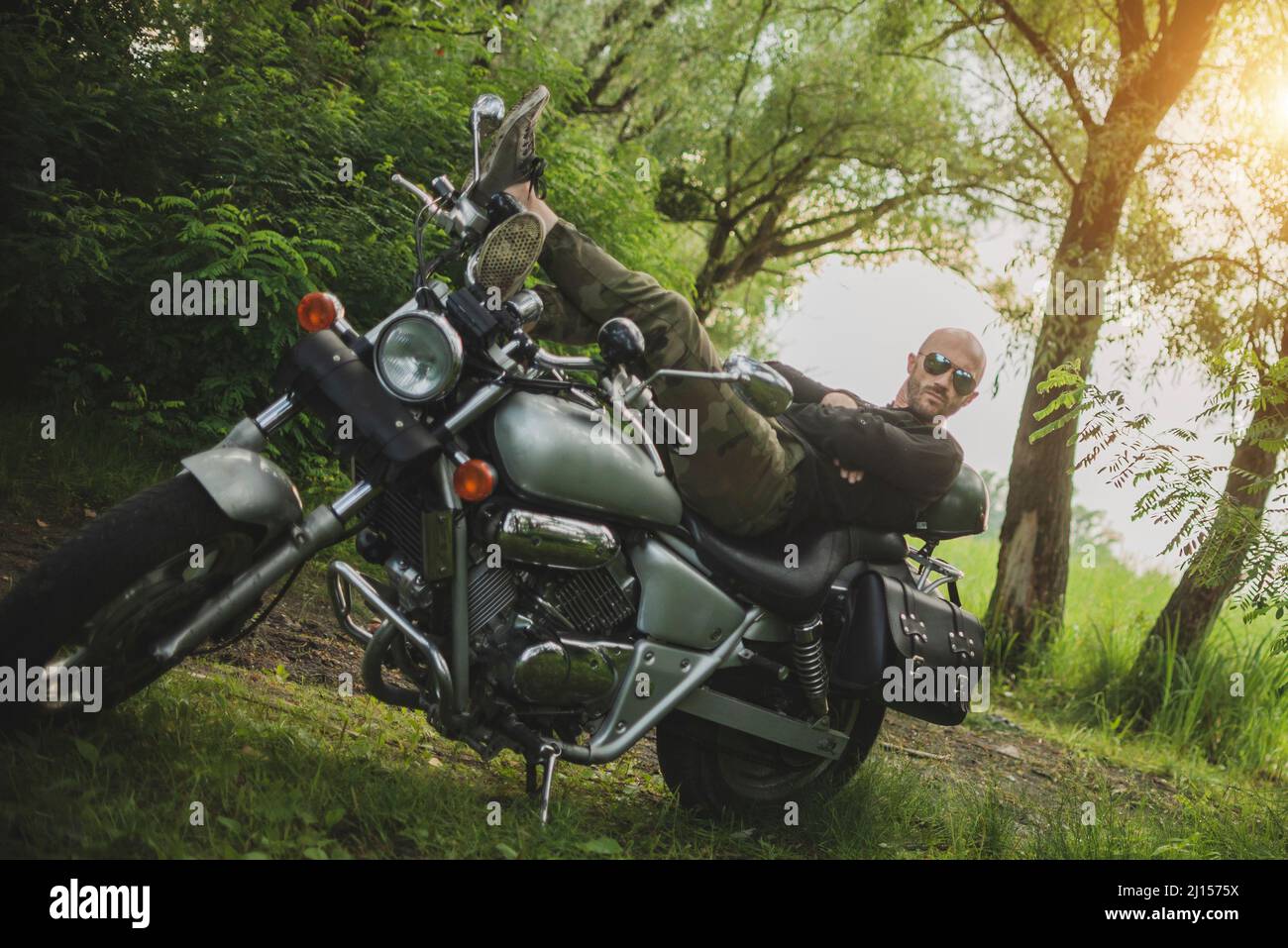 A man lies on a retro motorcycle on the background of nature. Retro ...