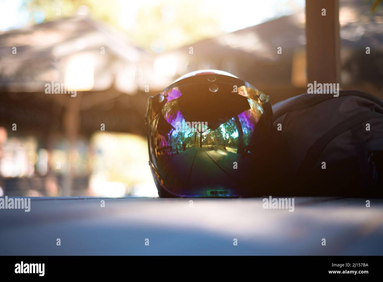 A motorcycle helmet with a mirror visor lies on the table with a ...