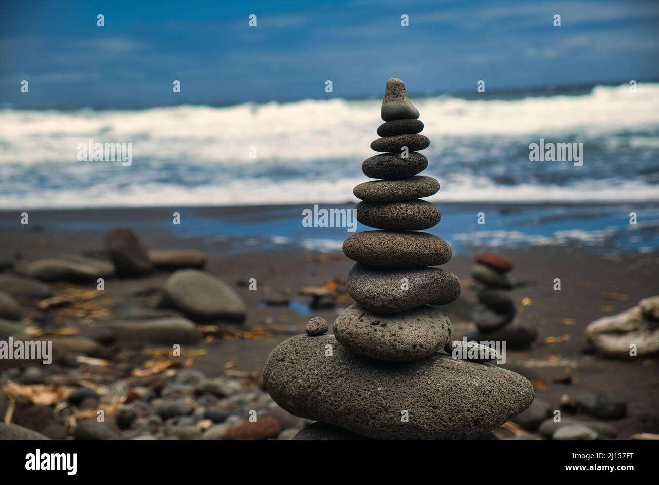 Round stones stacked on each other on the sandy beach on the coast ...