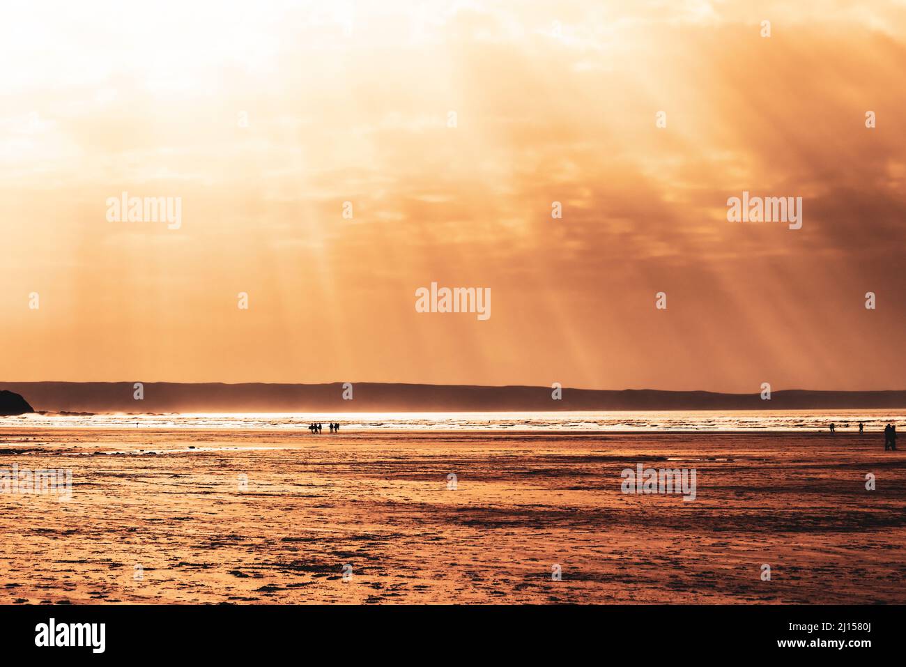 Rays of light and sunbeams shine down into a quiet sandy uk beach at ...