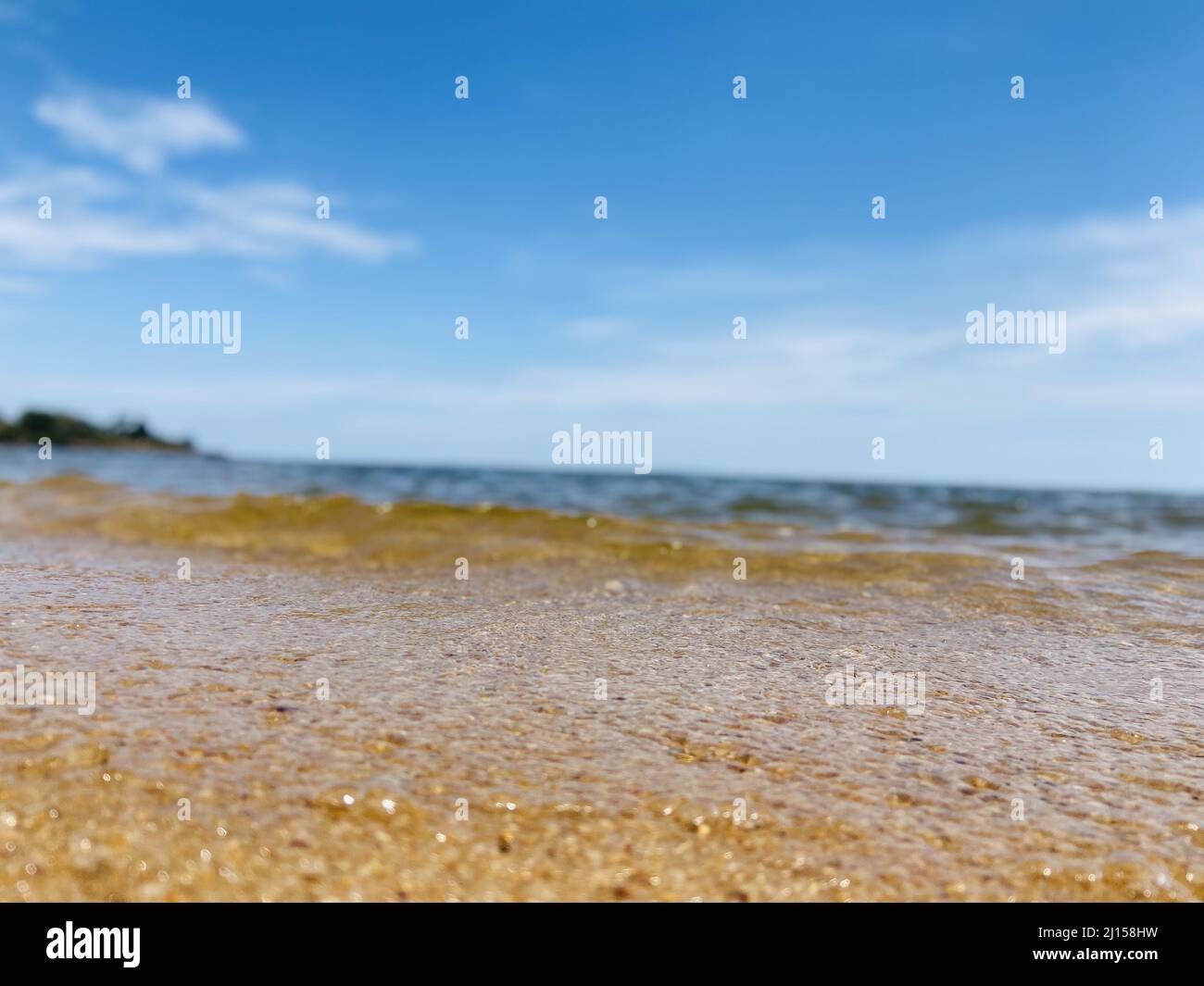 Shot of the water touching the beach on a sunny day Stock Photo - Alamy