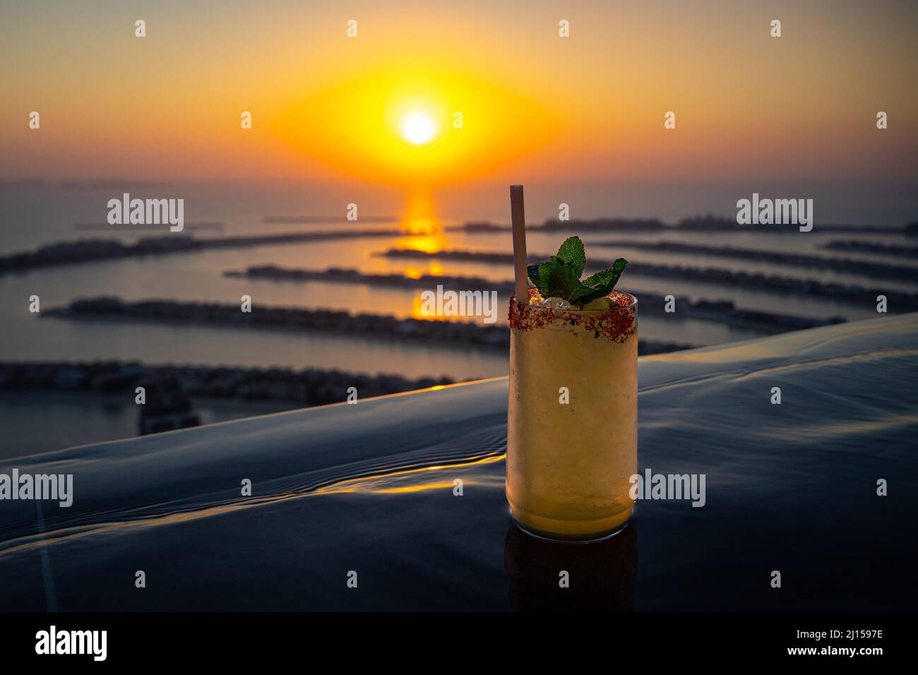 Yellow cocktail on the edge of an infinity pool with a beautiful ...