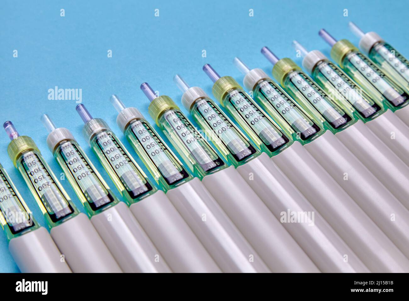 Diabetic insulin syringe pens lined up in a row on a blue background ...