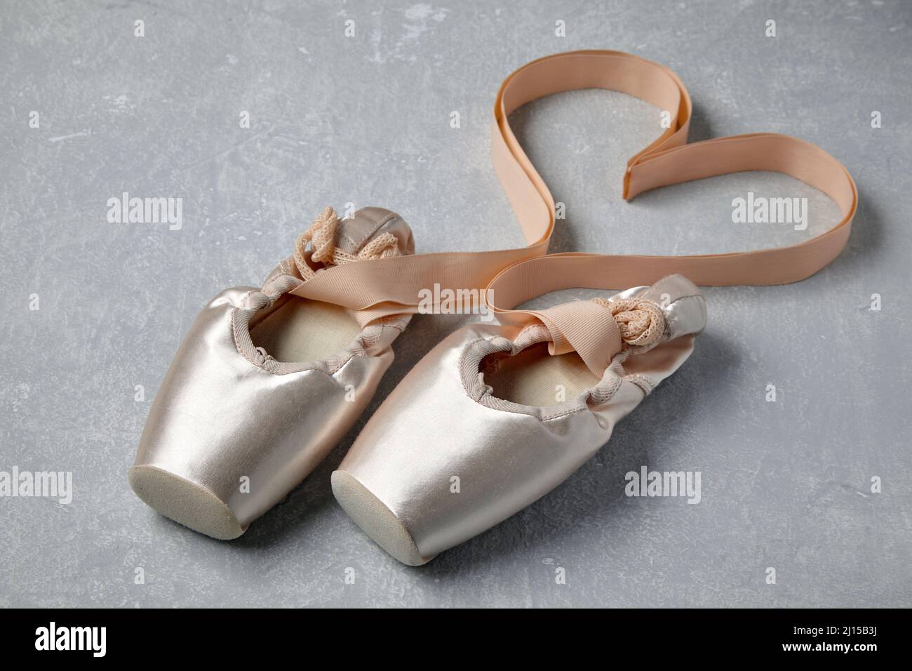 Beige pointe shoes with ribbons laid out in the shape of a heart on a ...