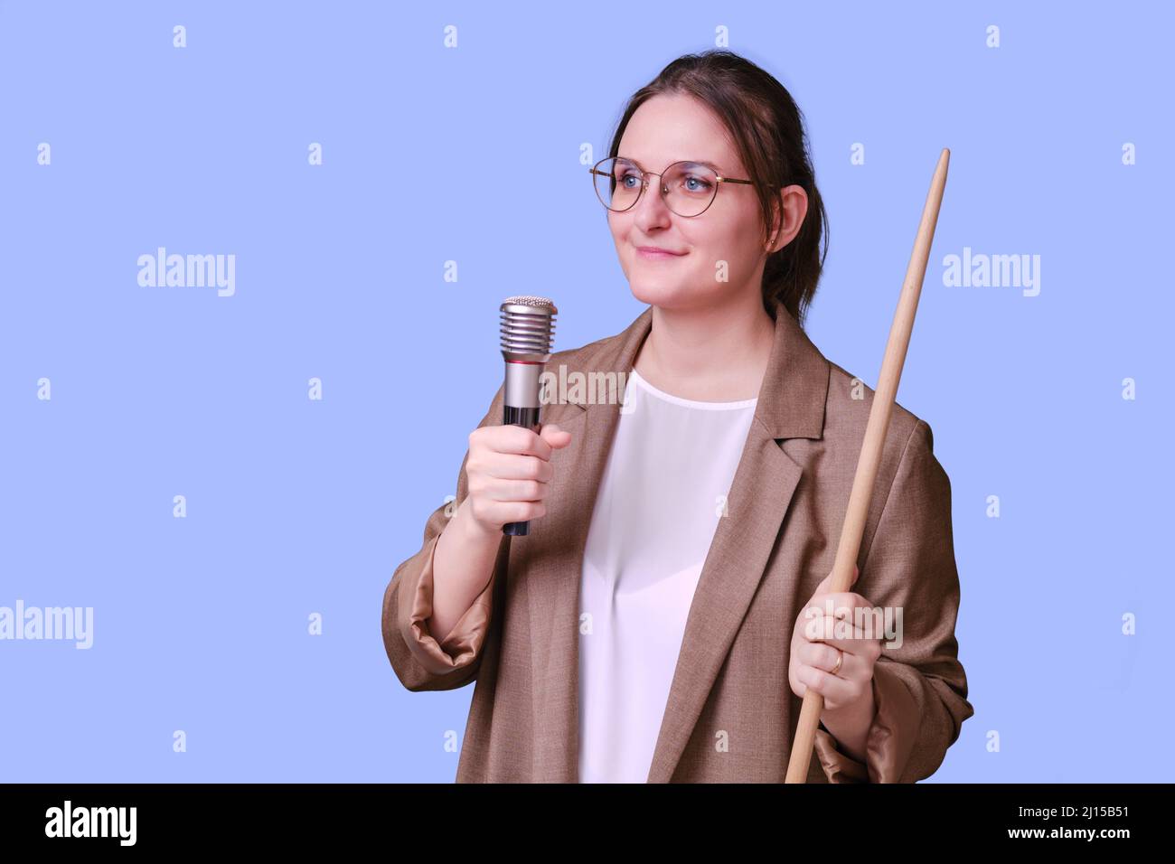 Happy woman teacher holding microphone on studio blue background, copy ...