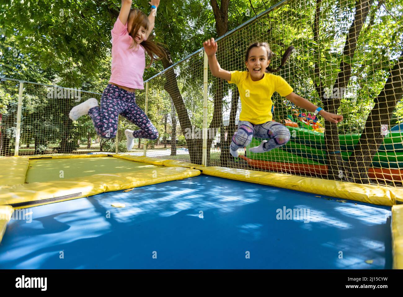 Little pretty girls having fun outdoor. Jumping on trampoline in ...