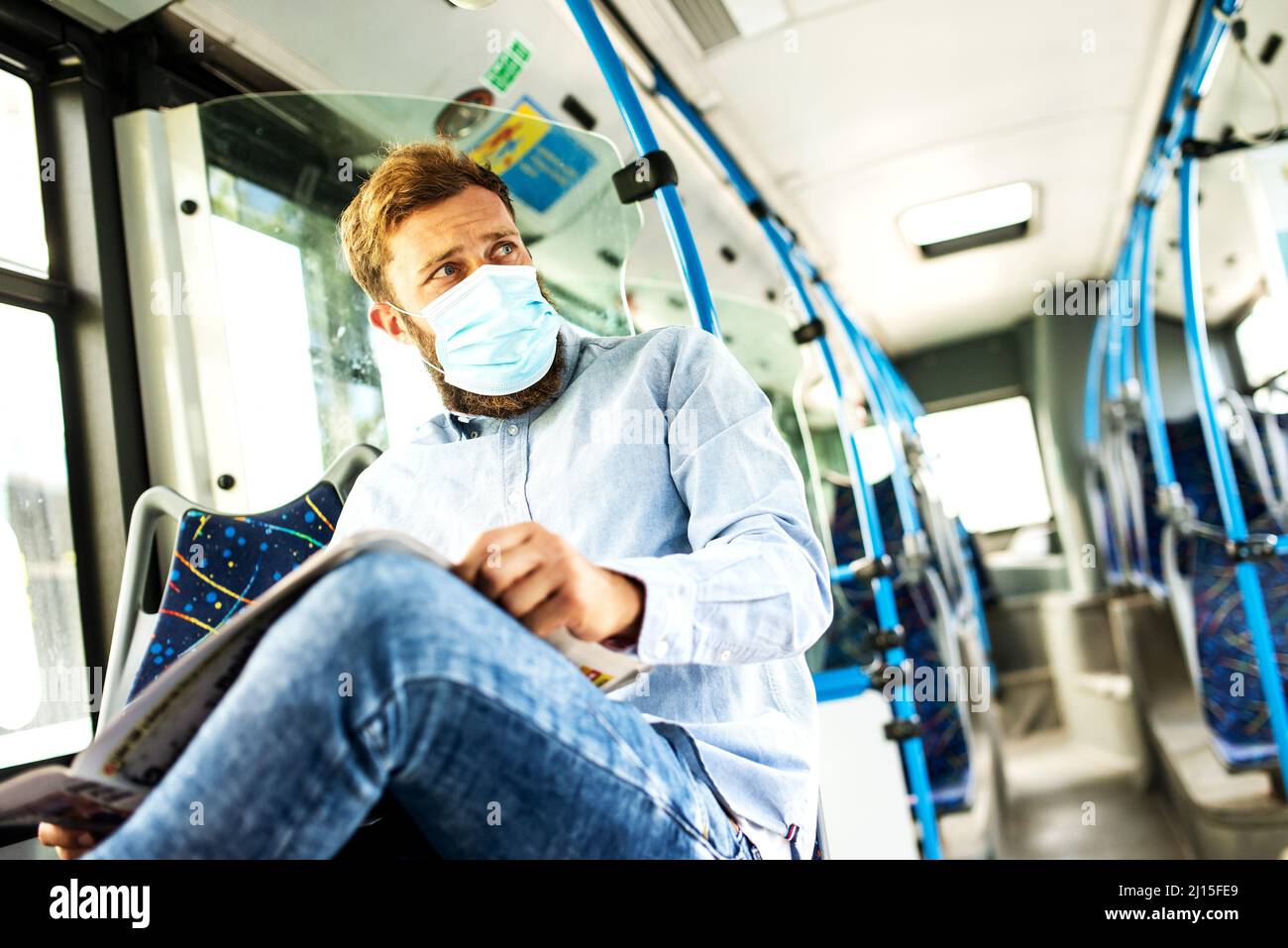 A handsome guy with a protective mask in public transport reads the ...