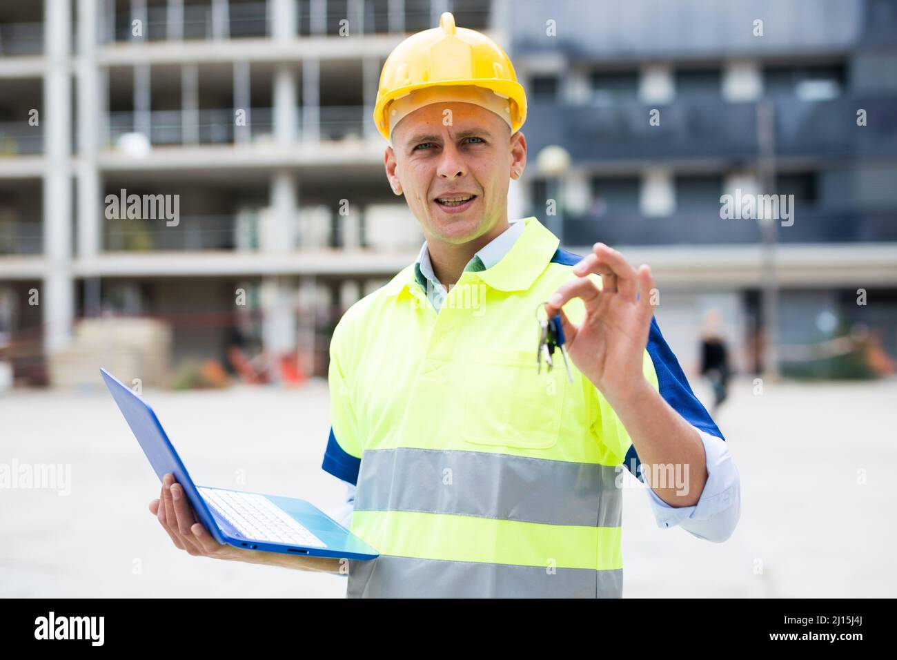 Engineer with laptop and keys in construction site Stock Photo - Alamy