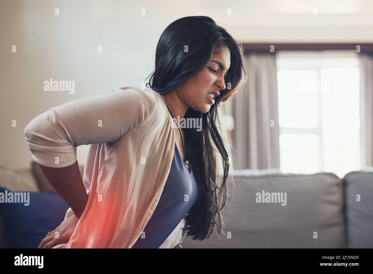 What was that sudden sharp pain. Shot of a young woman suffering with ...