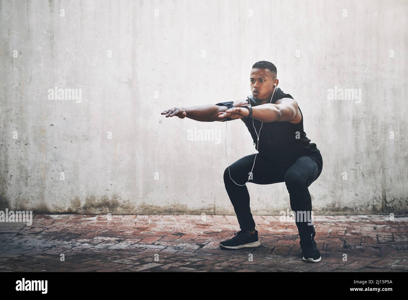 Get your squat on. Full length shot of a handsome young man listening ...