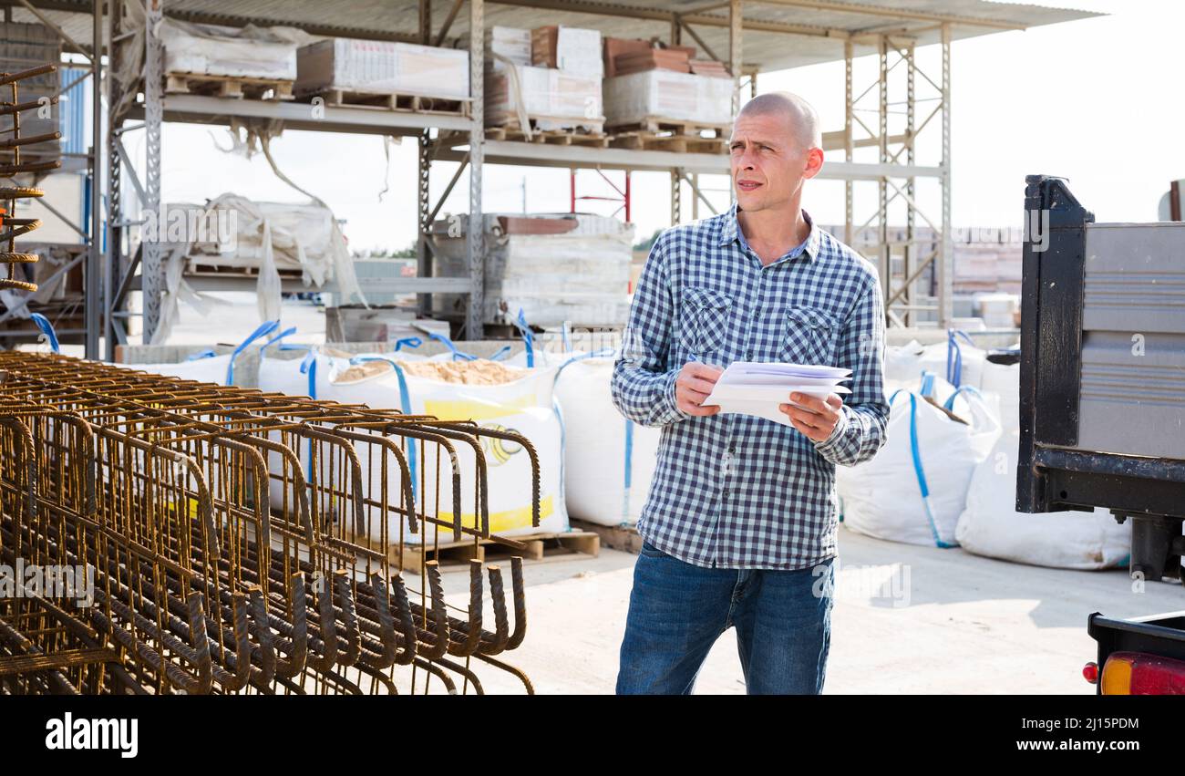 Man worker with papers collecting order at warehouse Stock Photo - Alamy