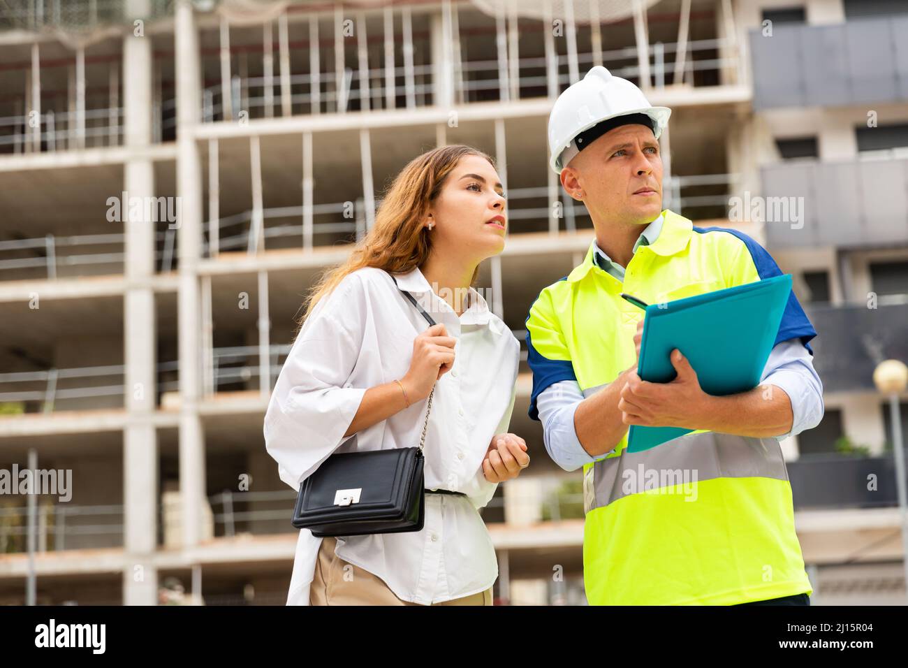 Builder talking with client at construction site Stock Photo - Alamy