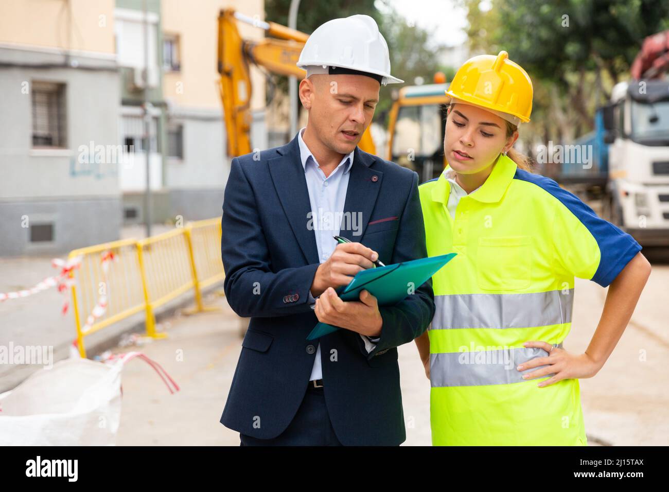 Civil engineer and a young woman worker discuss a construction plan ...