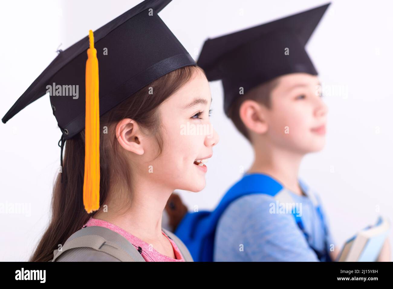 Side view of Happy boy and girl in graduation cap holding books Stock ...